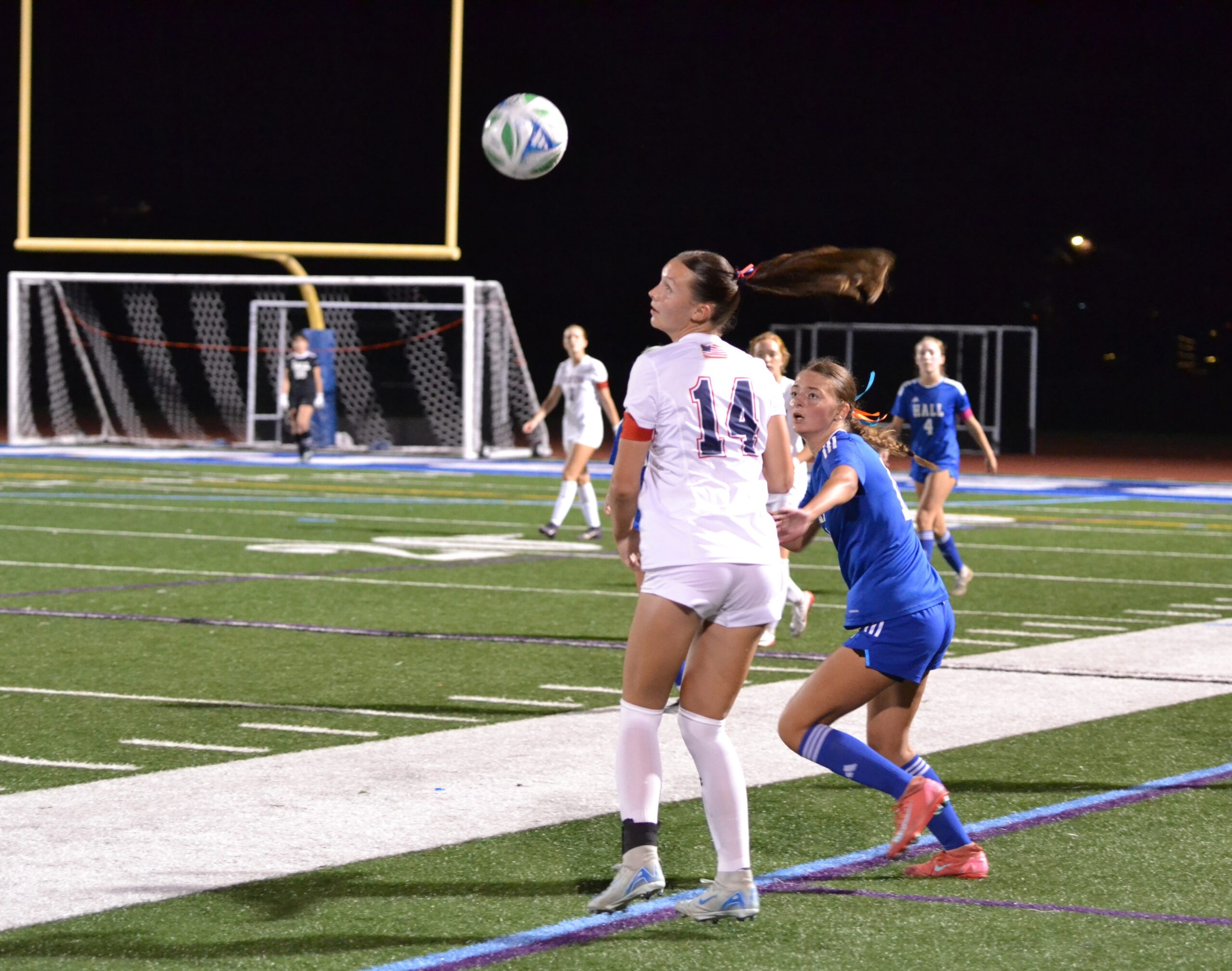 Hannah Wittig (14) and Hall's Maya Reilly work for control of the ball ...