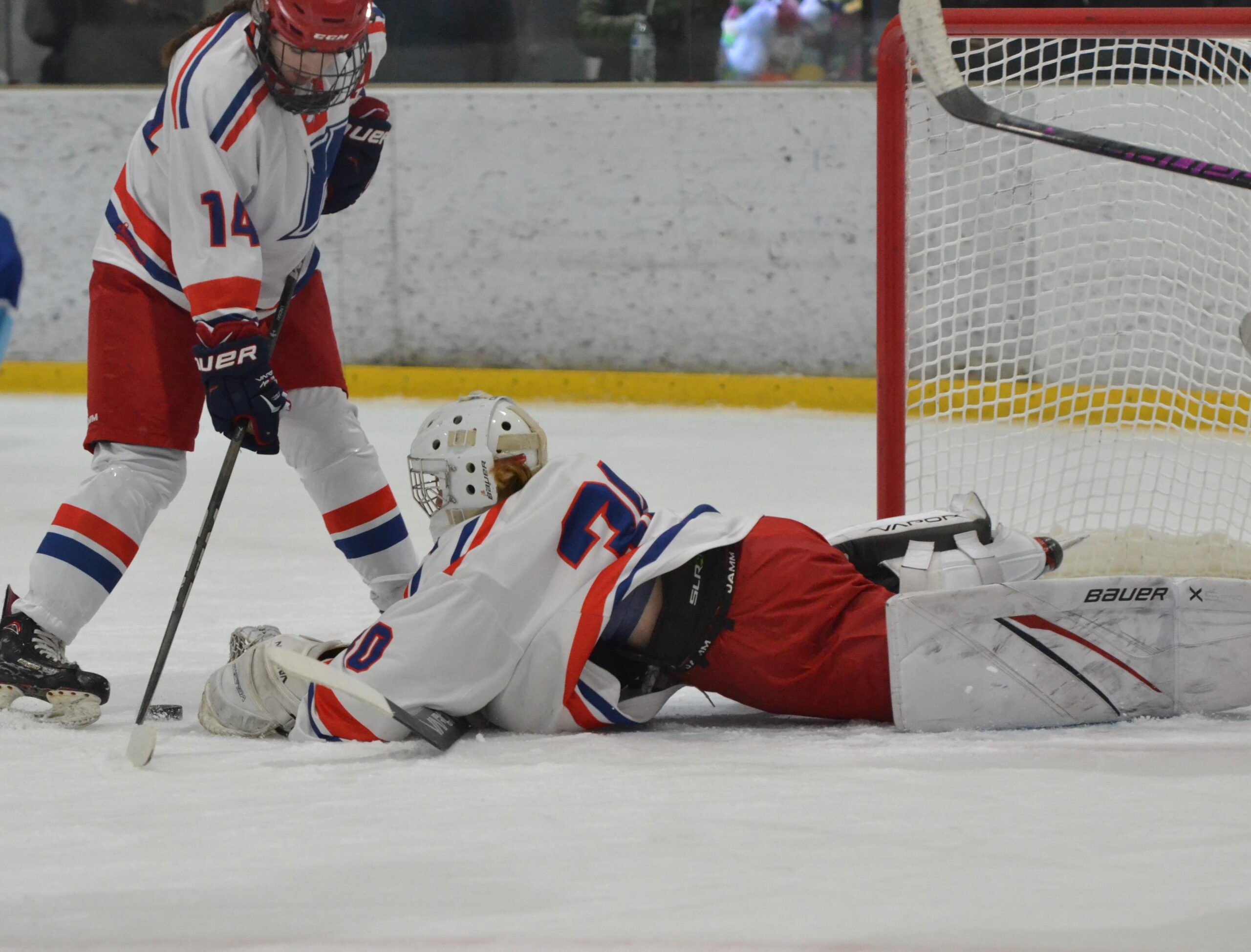 The puck eludes Claire Reidel (14) and Lauren Busi in front of the goal ...
